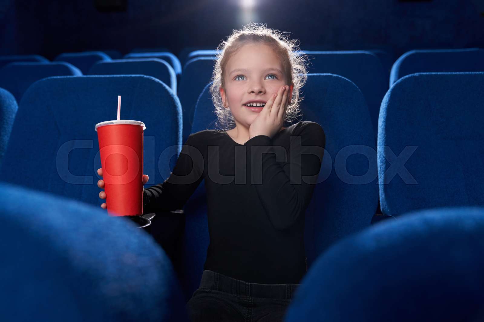 Fascinated girl watching movie in theatre. | Stock image | Colourbox