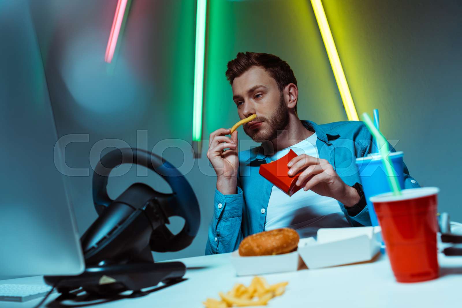 handsome and good-looking man eating french fries and looking at ...
