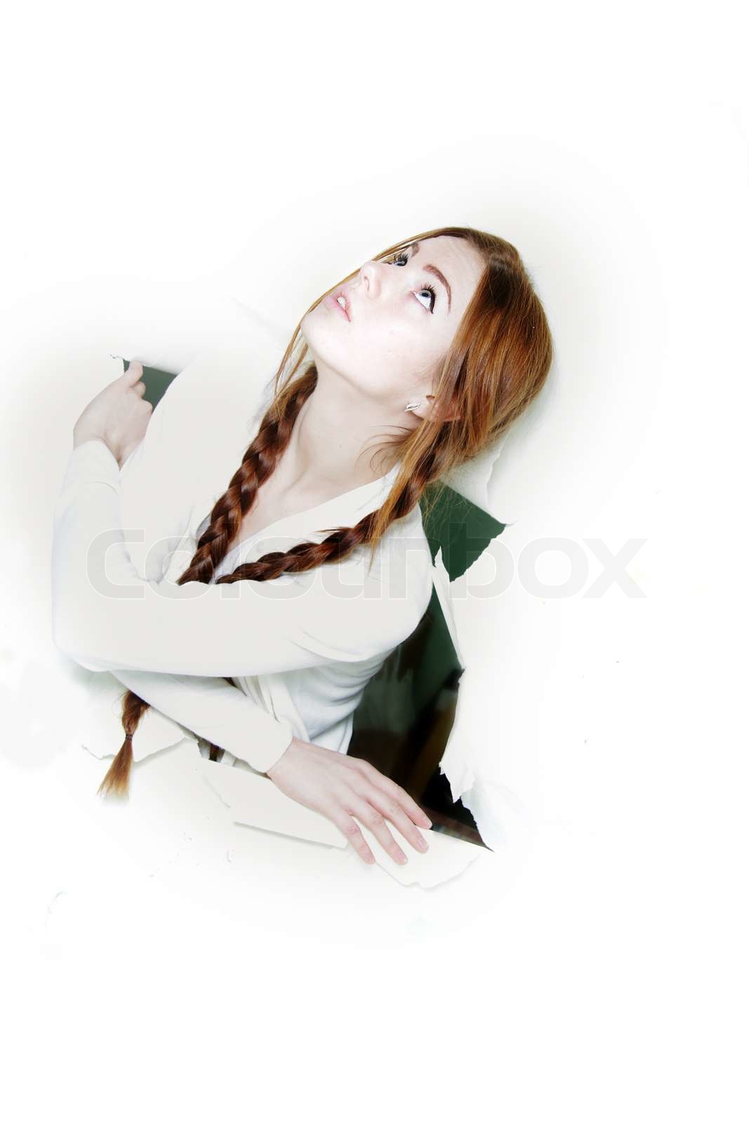 young woman looking out up from hole in paper | Stock image | Colourbox
