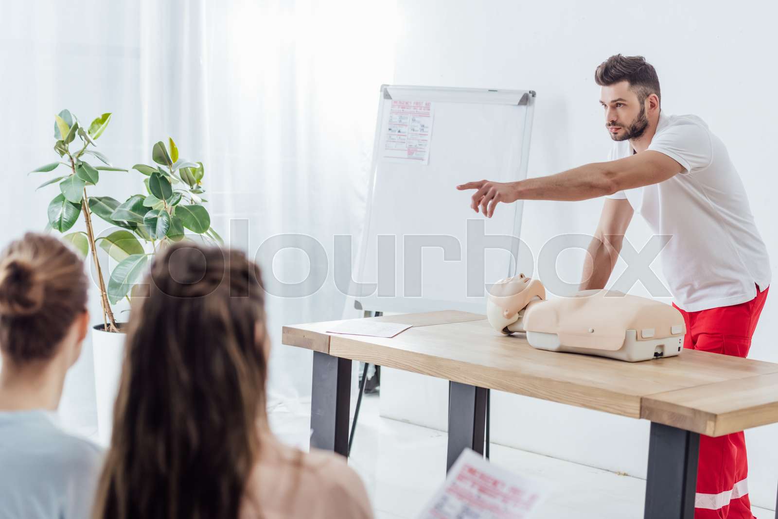 handsome instructor with cpr dummy pointing with finger during first ...