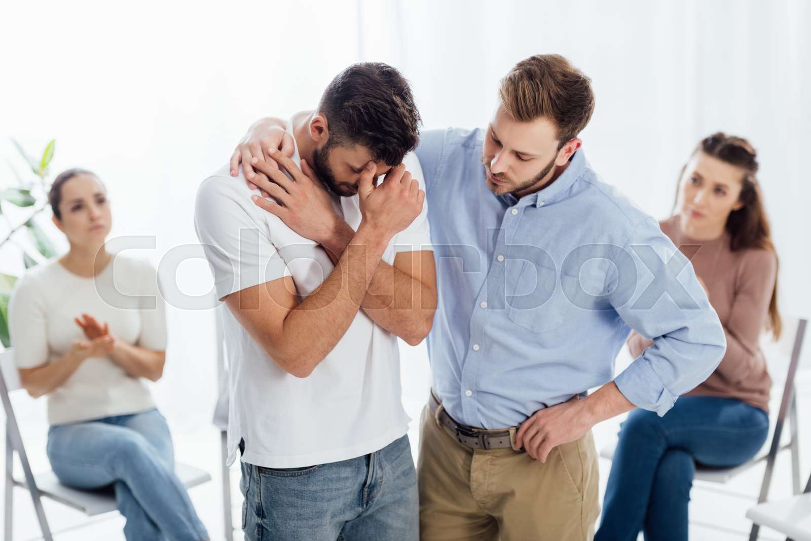 man cheering another man while people sitting on chairs during group ...