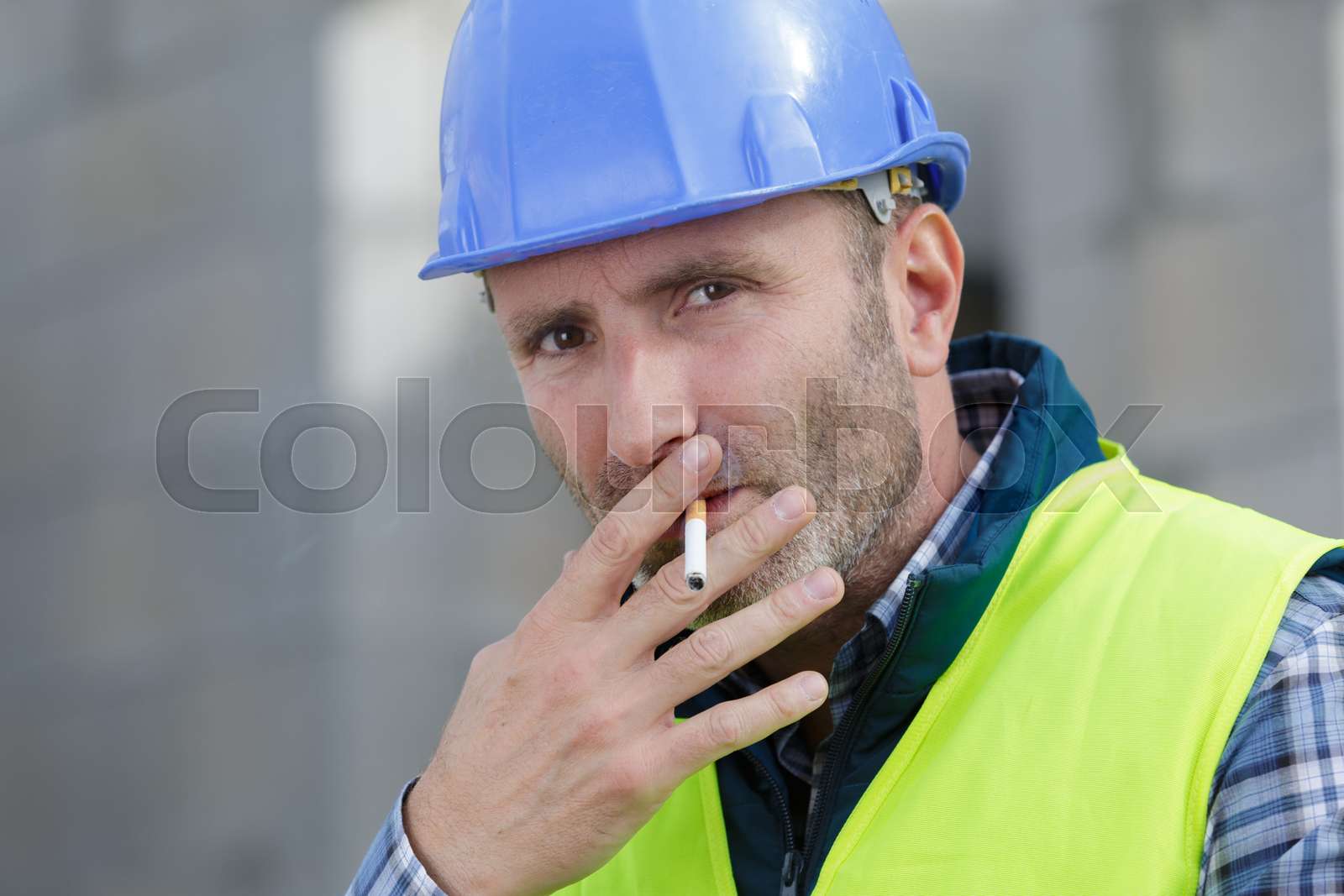 happy builder smoking cigarette outdoors | Stock image | Colourbox