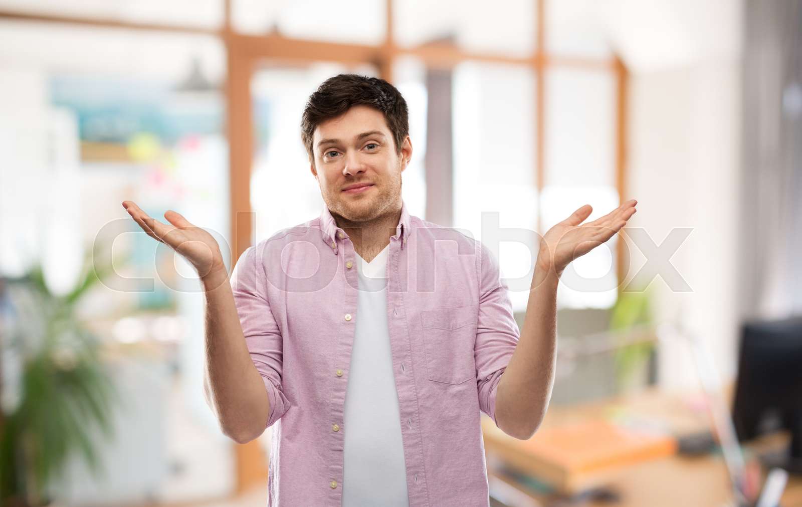 young man shrugging over office room | Stock image | Colourbox