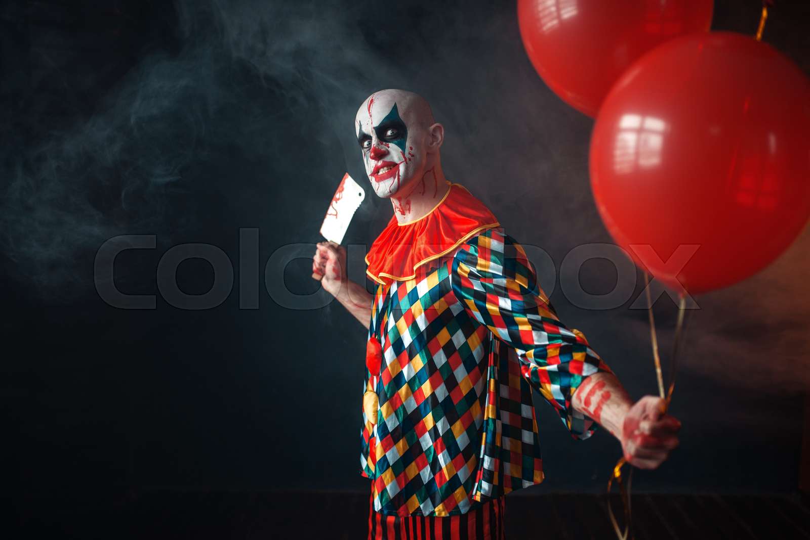 Bloody clown with meat cleaver holds air balloon | Stock image | Colourbox