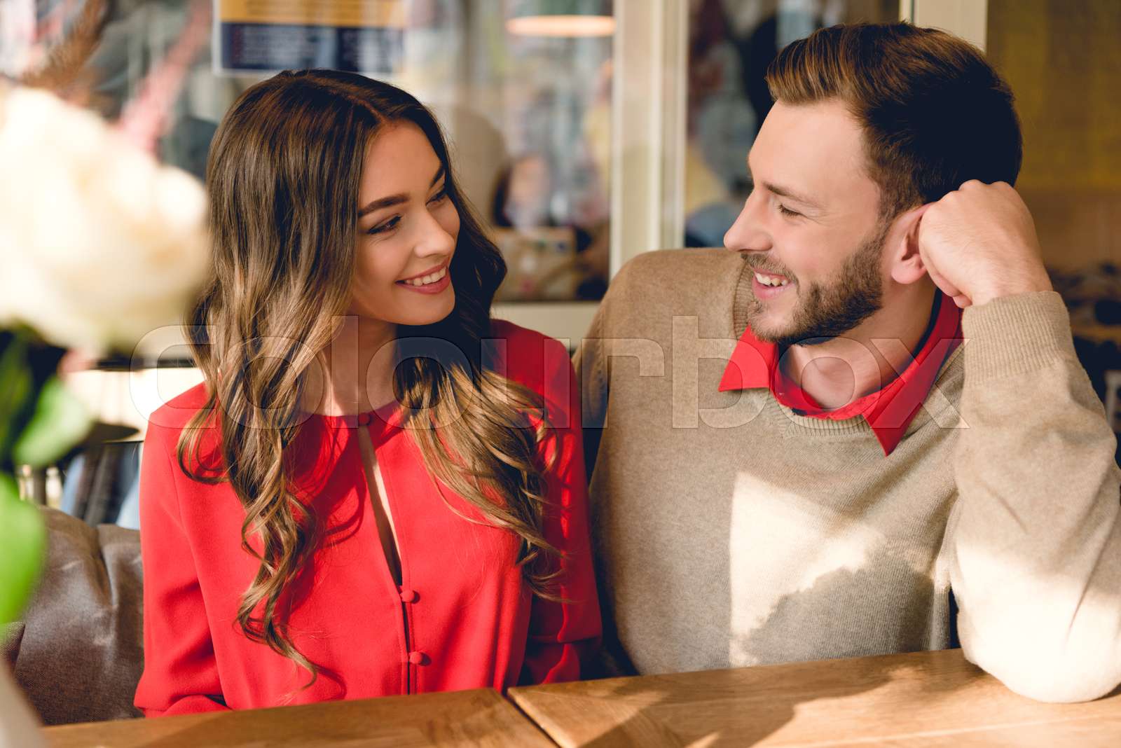 handsome bearded man smiling while looking at beautiful girl in cafe ...