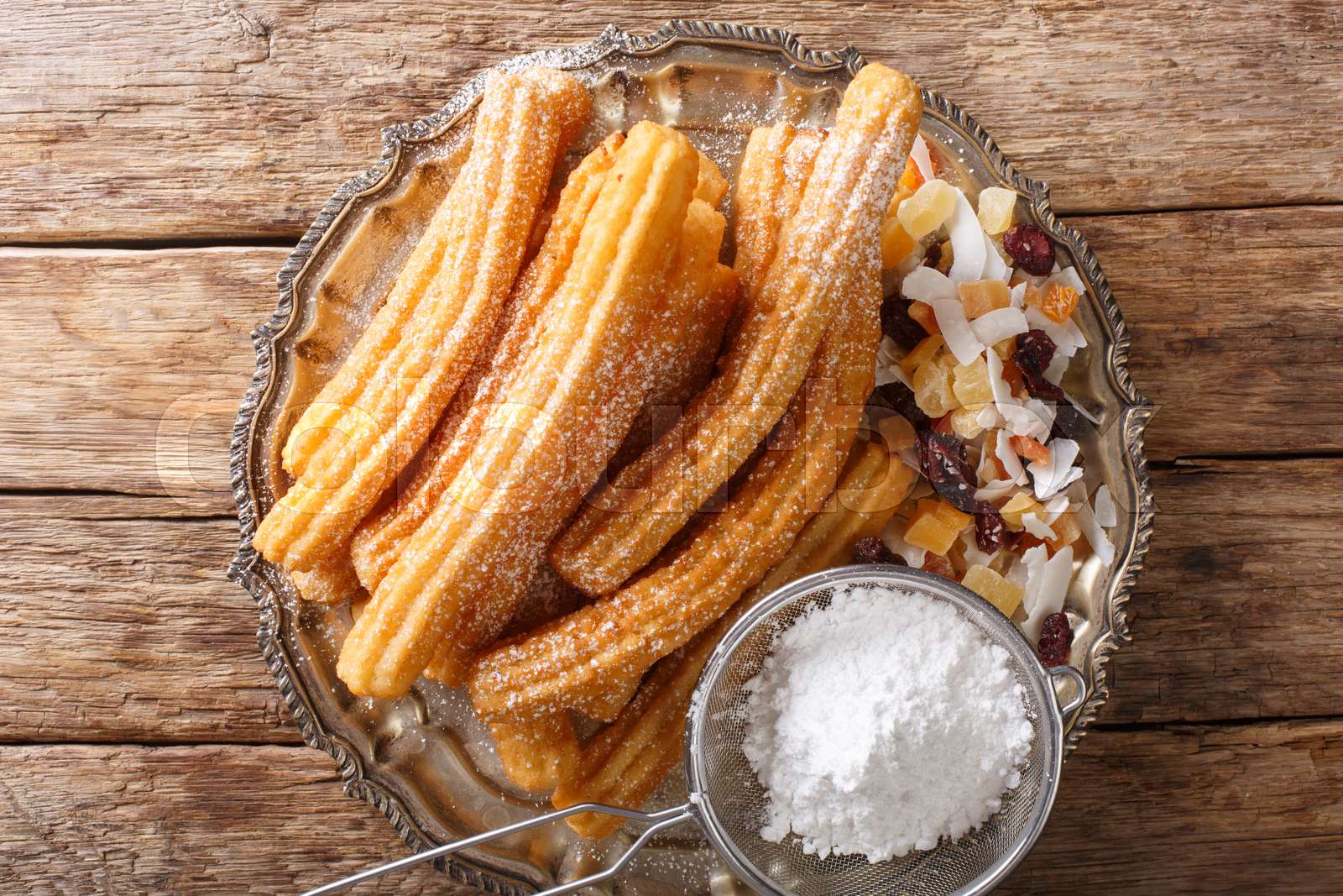 Delicious homemade churros with icing sugar and candied fruits close-up ...