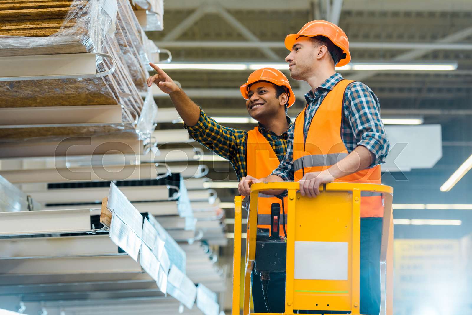 smiling indian warehouse worker pointing with finger at construction ...