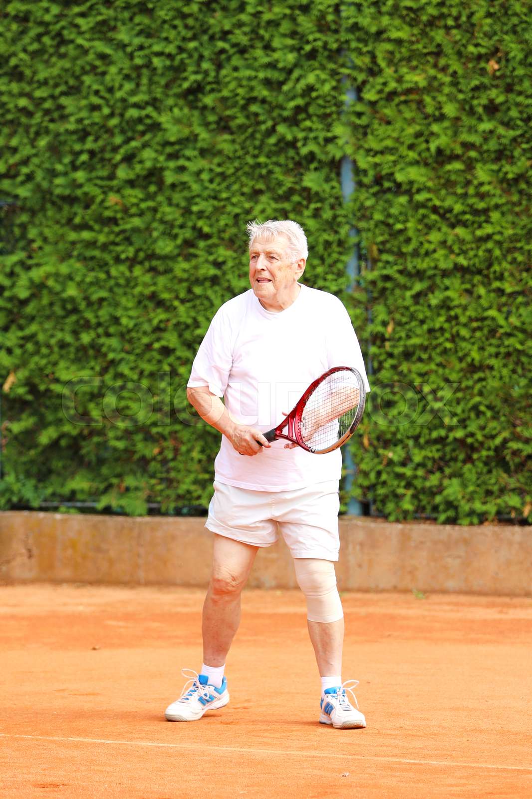 Old man with racket wait for returning ball | Stock image | Colourbox
