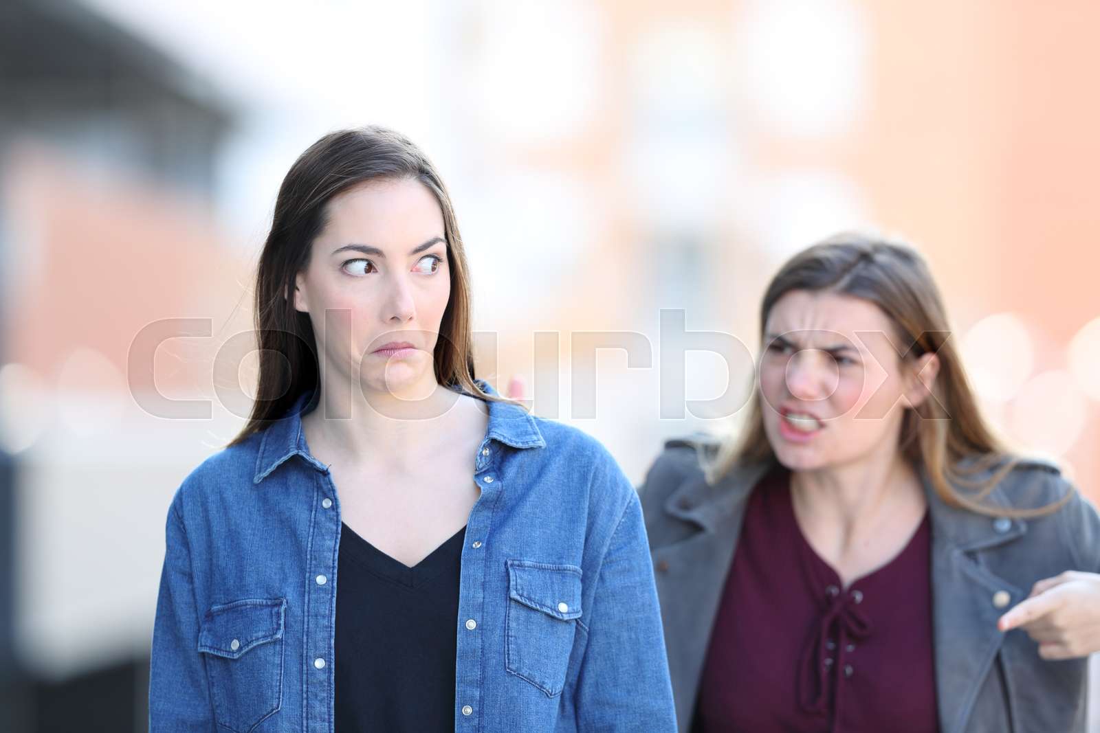 Angry woman scolding her confused friend in the street | Stock image ...