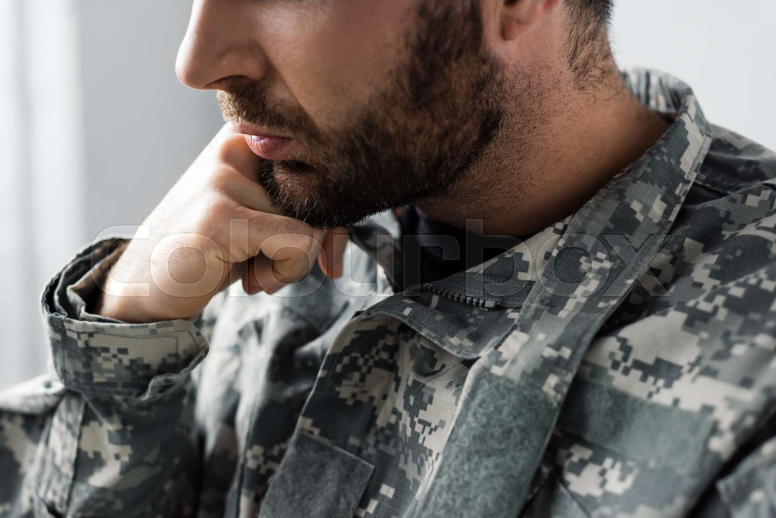 partial view of bearded military man in uniform holding hand near face ...