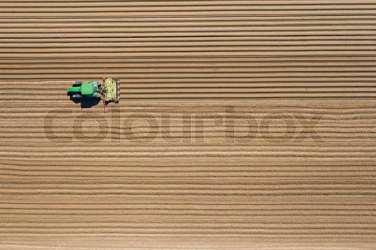 Aerial view of farming tractor plowing and spraying on field ...