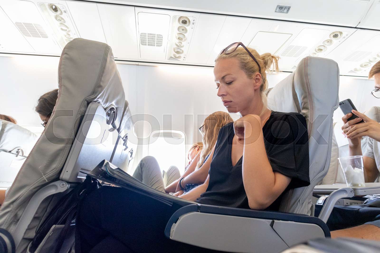 Woman reading magazine on airplane during flight. Female traveler ...
