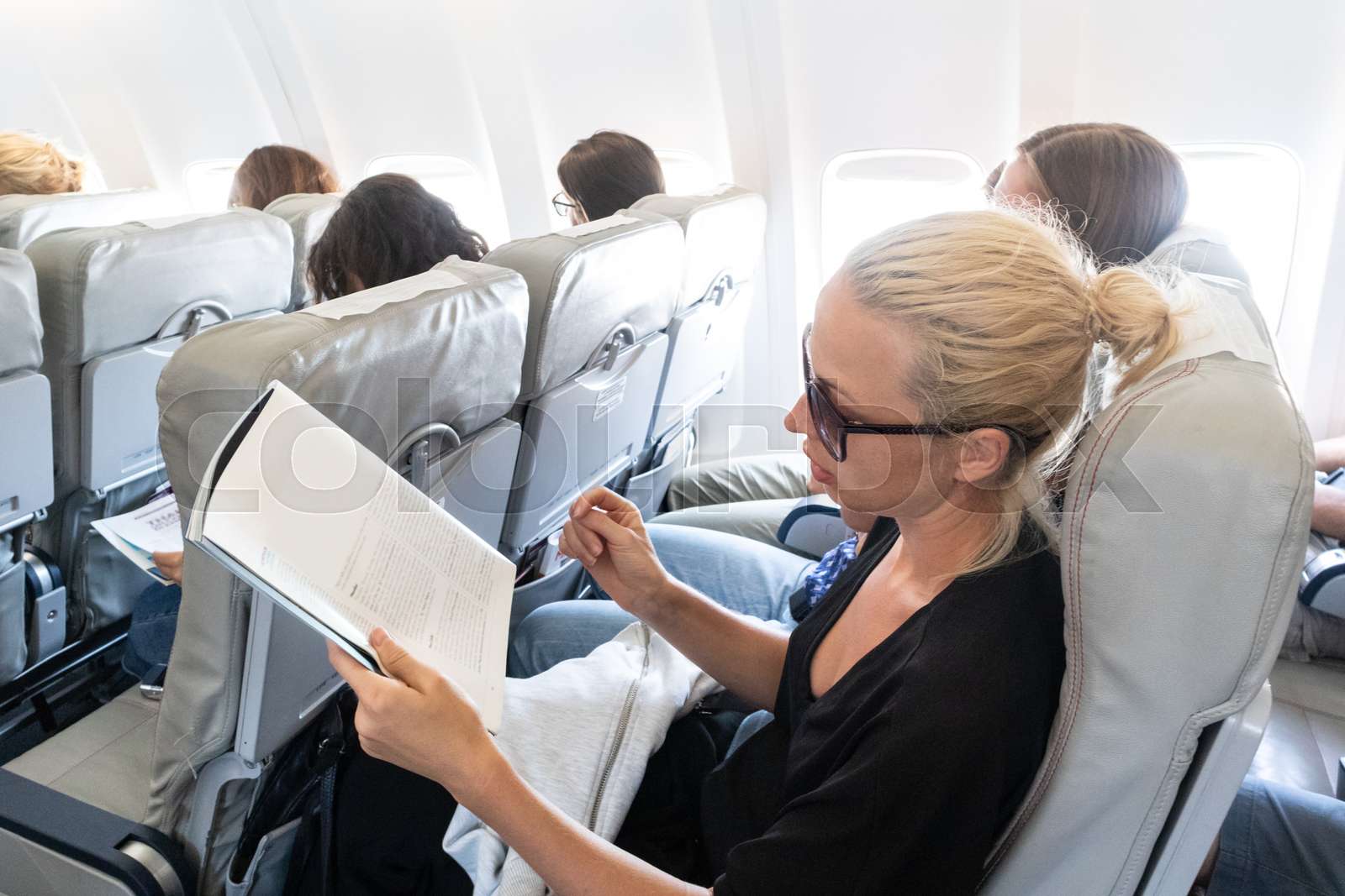 Woman reading magazine on airplane during flight. Female traveler ...