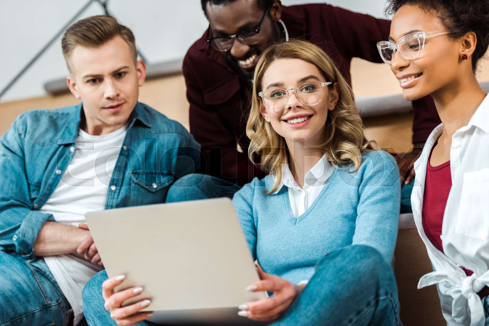 smiling multicultural students with laptop in lecture hall | Stock ...
