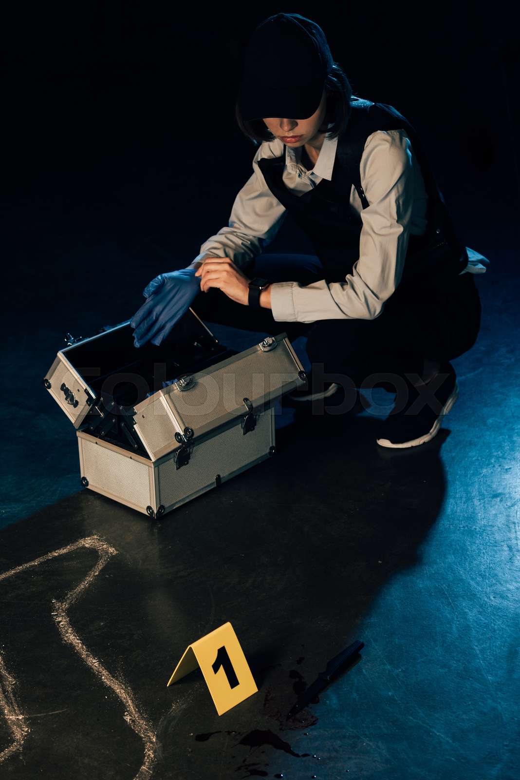 investigator with investigation kit putting on rubber glove at crime ...