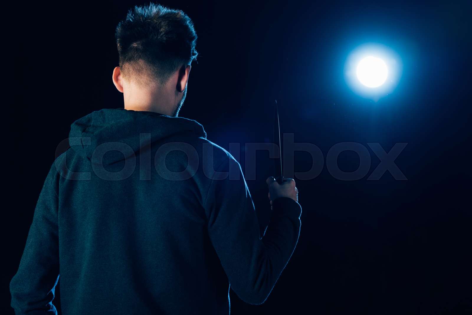 back view of killer holding knife isolated on black | Stock image ...