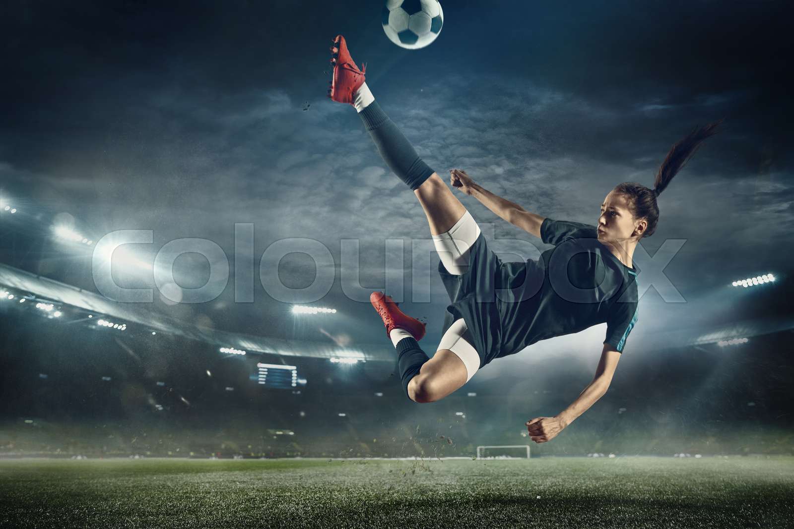 Female soccer player kicking ball at the stadium | Stock image | Colourbox