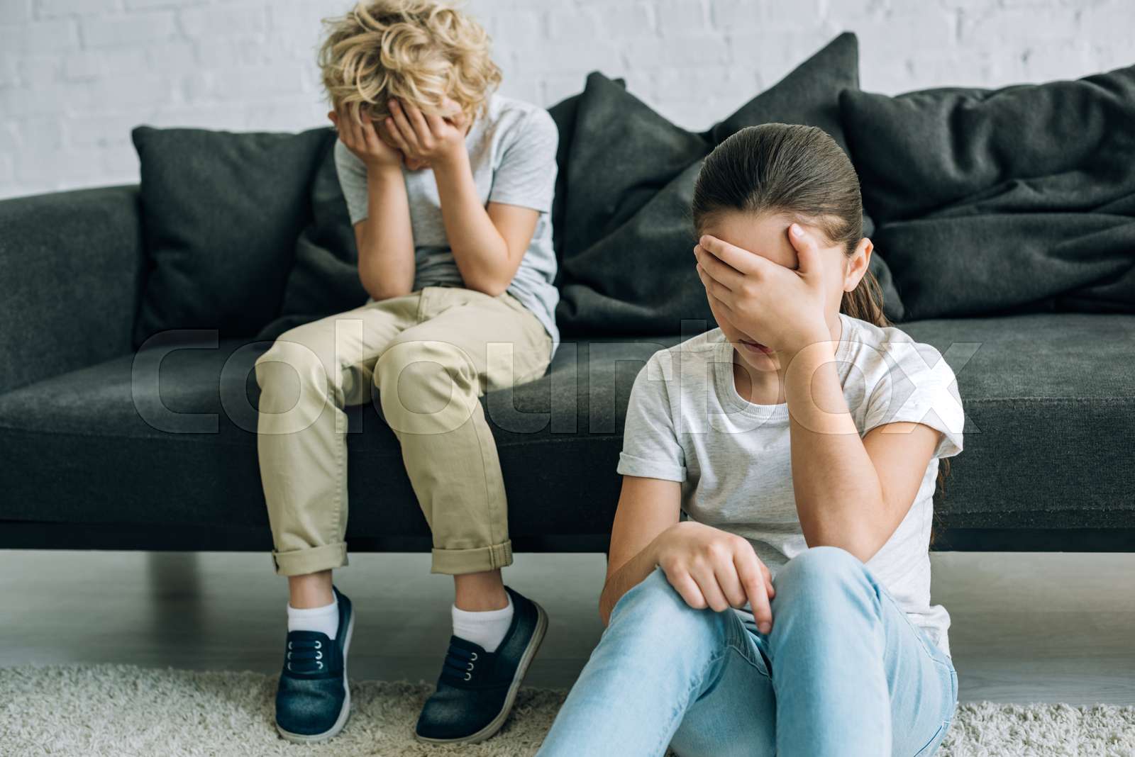 two sad preteen kids crying in living room | Stock image | Colourbox