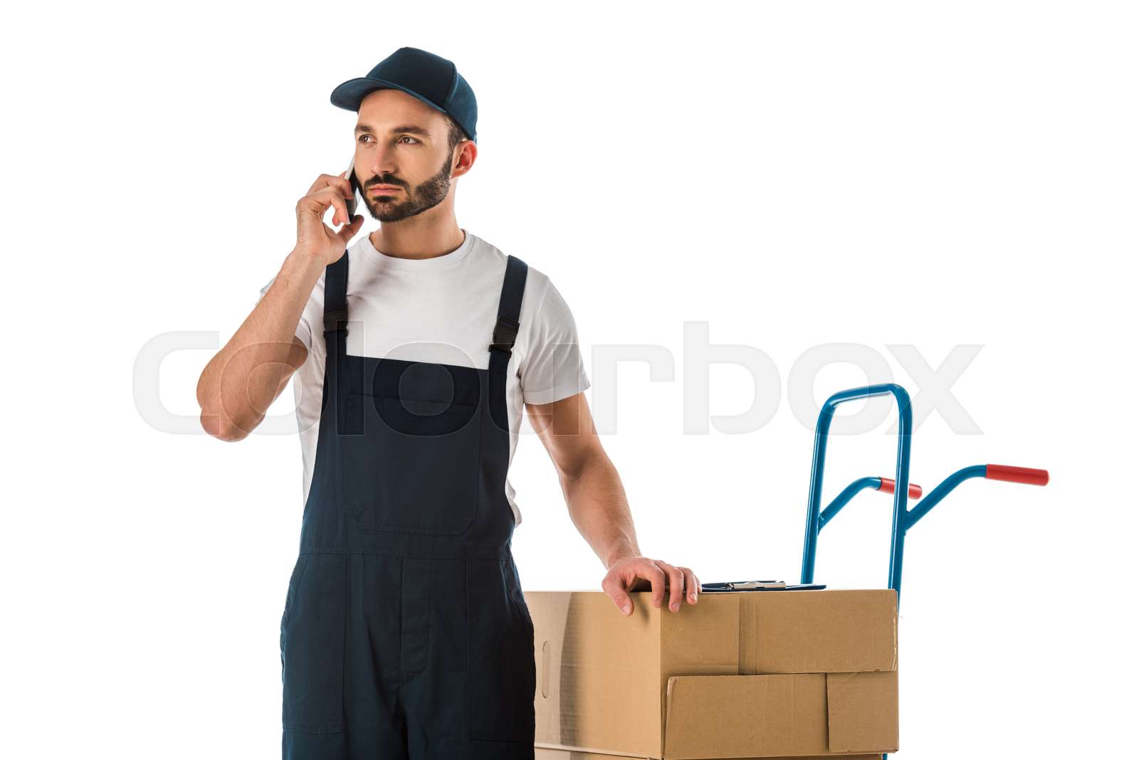 serious delivery man talking on smartphone while standing near ...
