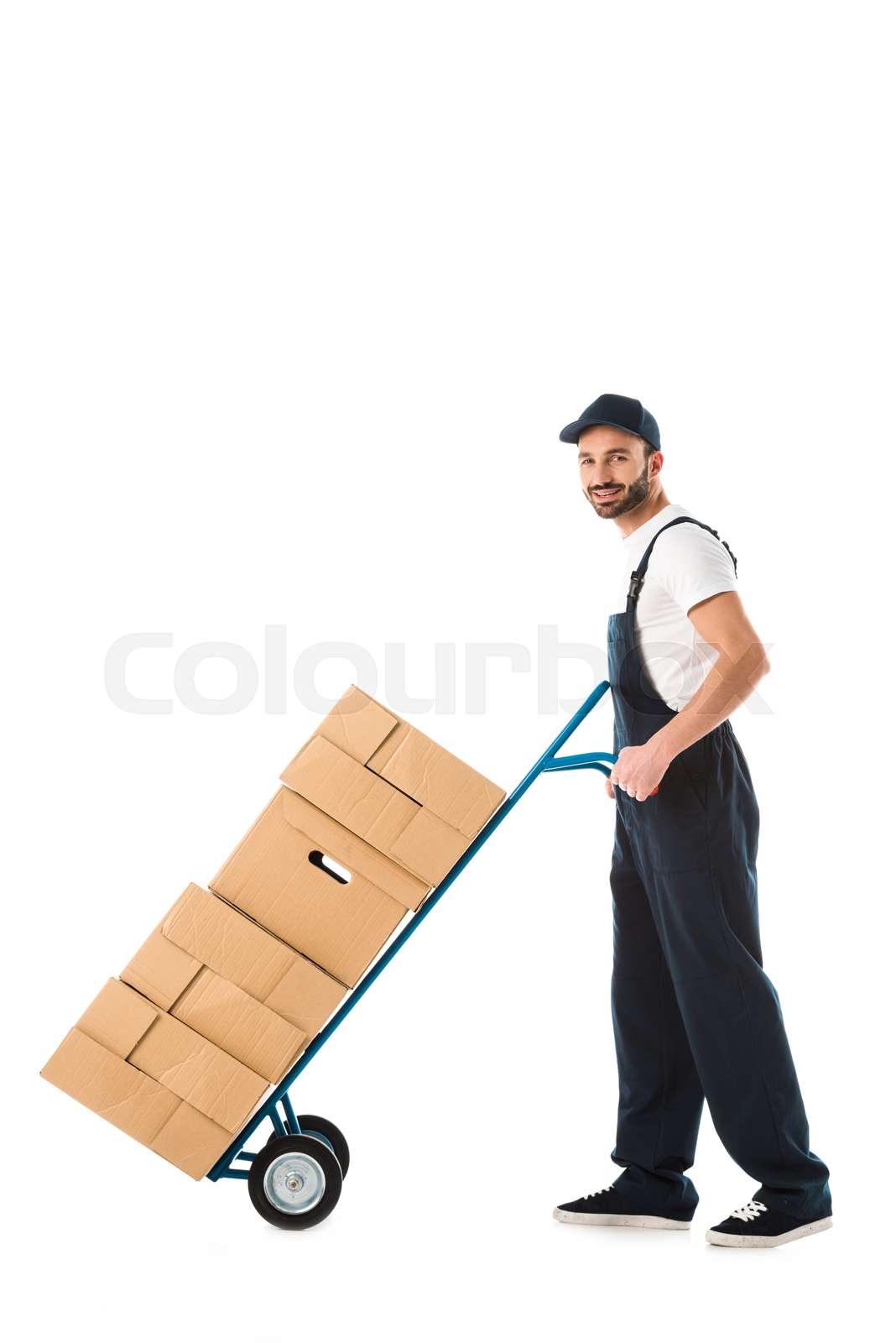 smiling delivery man transporting hand truck loaded with carton boxes ...
