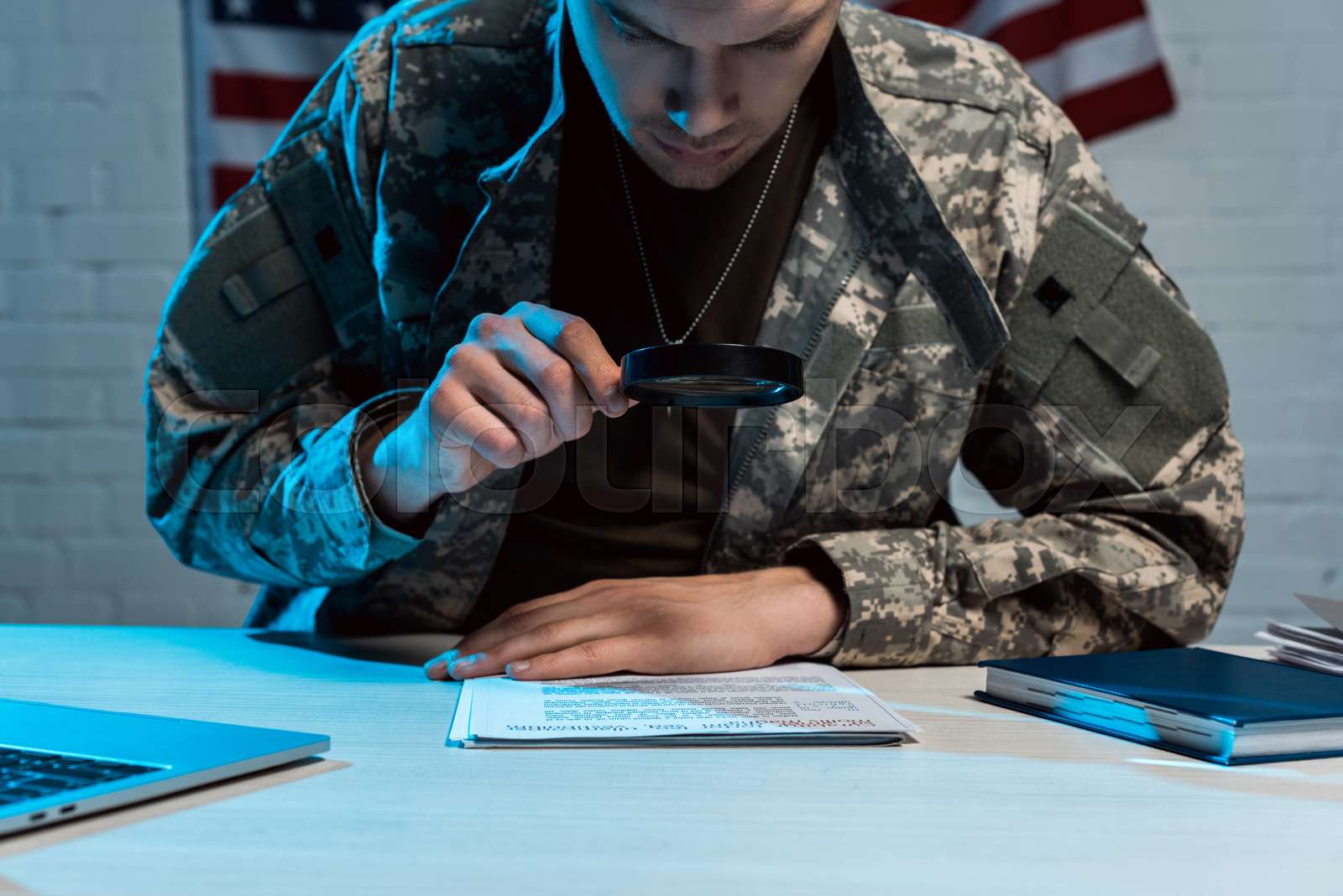 handsome soldier holding magnifying glass while reading document in ...