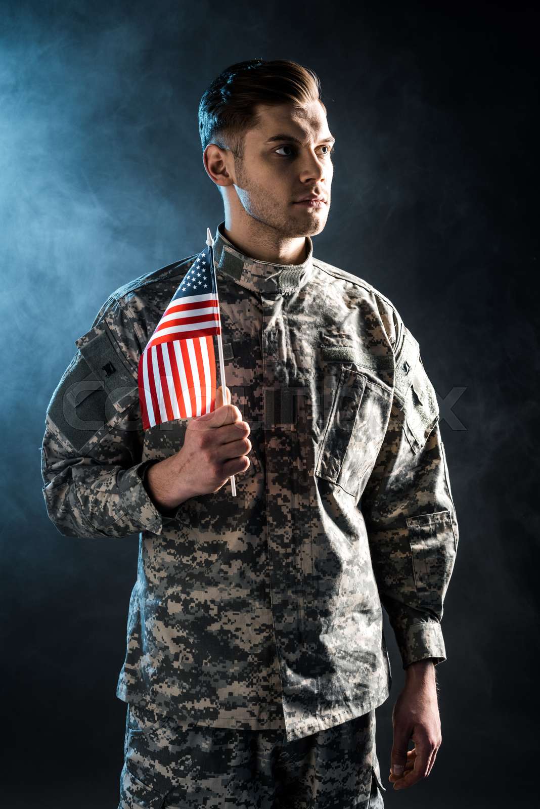 confident soldier in military uniform holding american flag on black ...