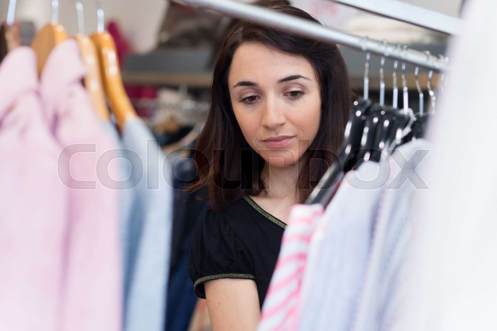 store assistant sorting clothes on stores rails | Stock image | Colourbox