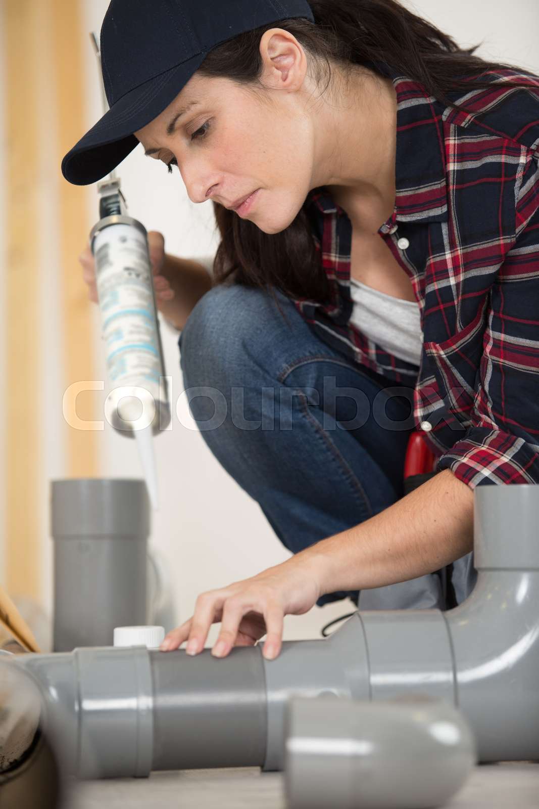 female plumber using silicone during pipes assembly | Stock image ...