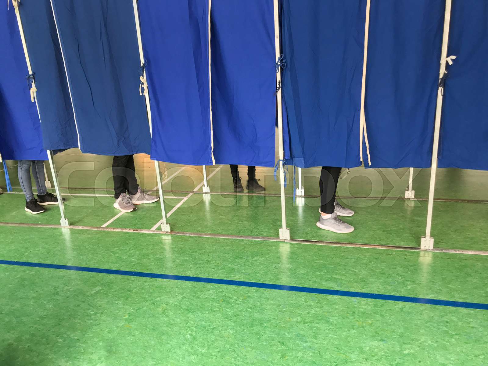 People voting in polling booths at a voting station at a school gym ...
