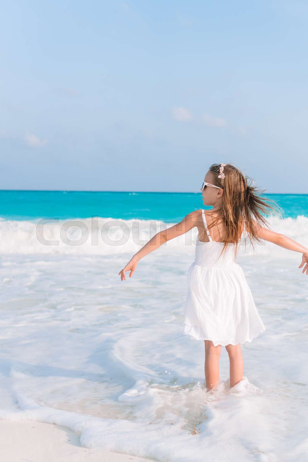 Active little girl at beach having a lot of fun on the shore making a leap | Stock image | Colourbox