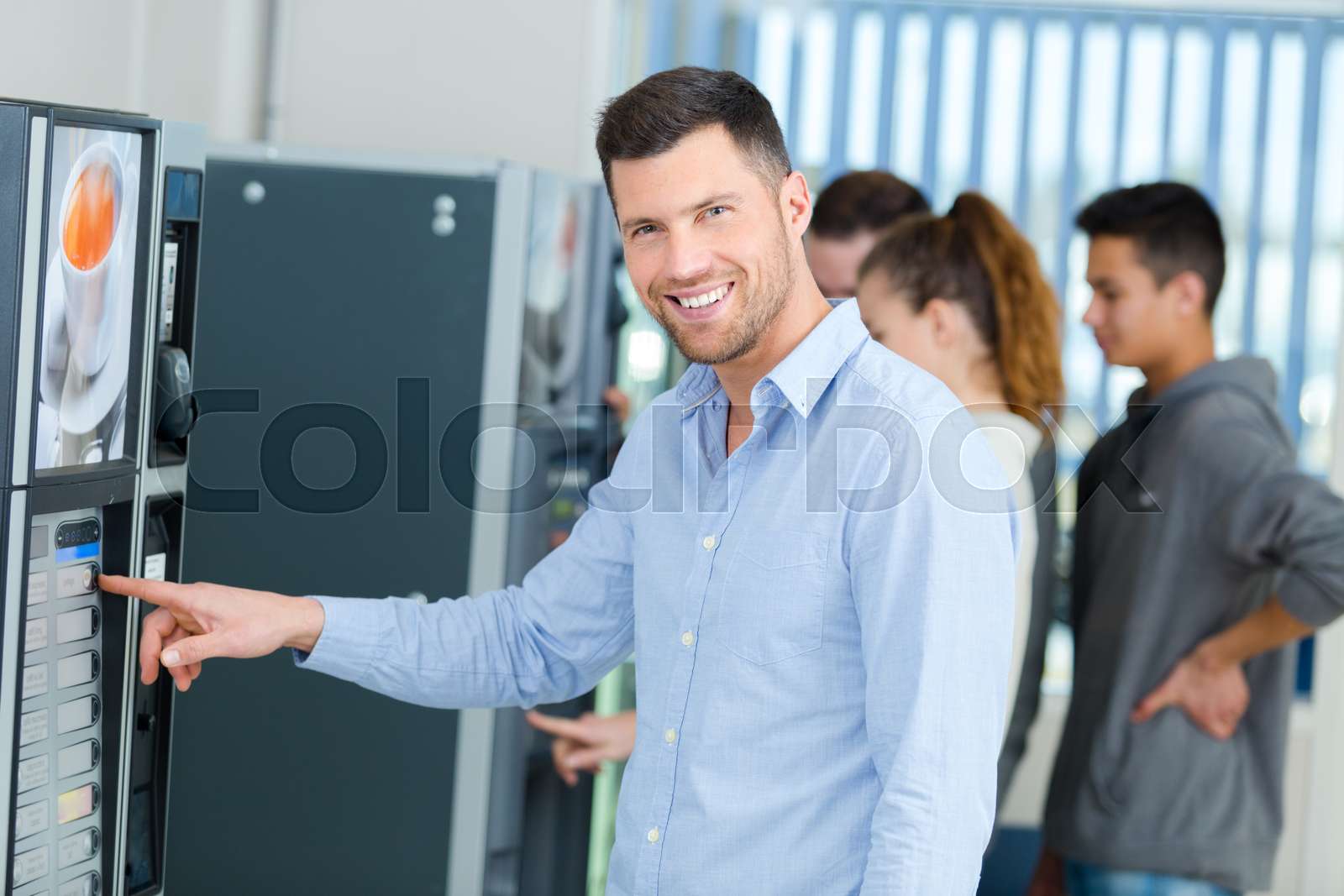 man posing while pressing vending machine | Stock image | Colourbox