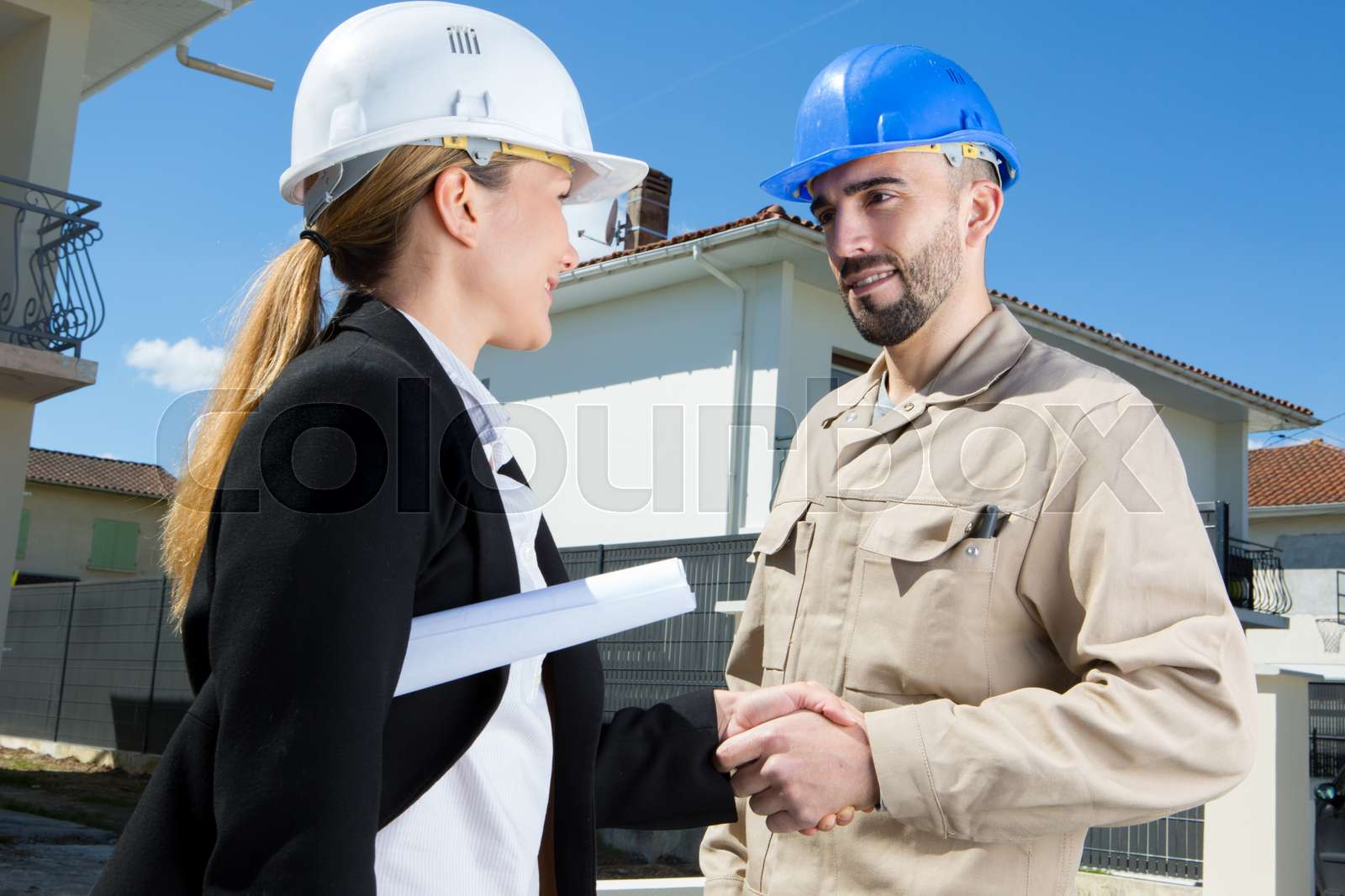 suited woman shaking hands with workman by residential property | Stock ...
