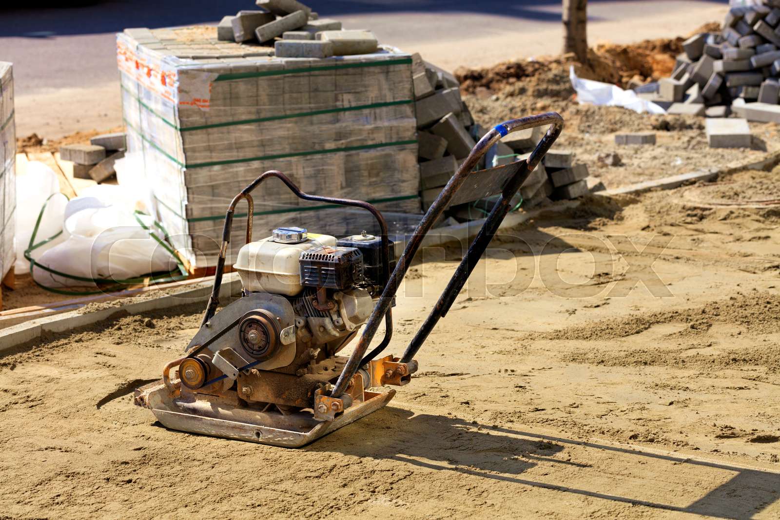 An old gasoline compactor for compacting sandy soil stands opposite a ...