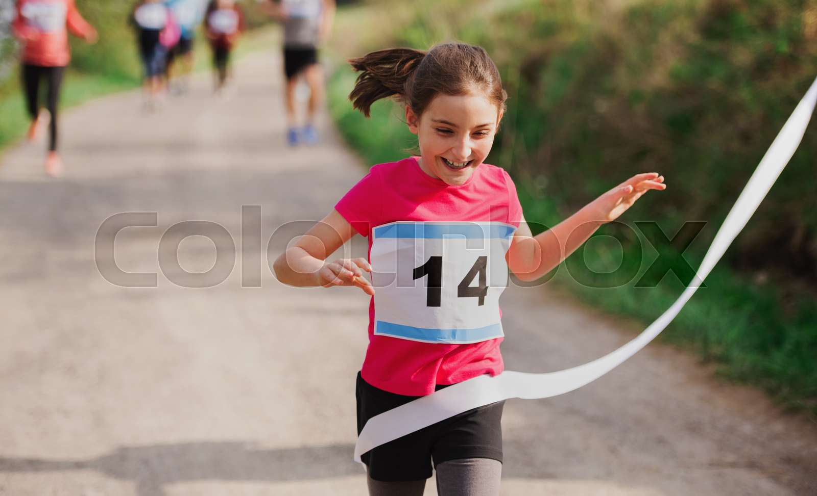 Small girl runner crossing finish line in a race competition in nature ...