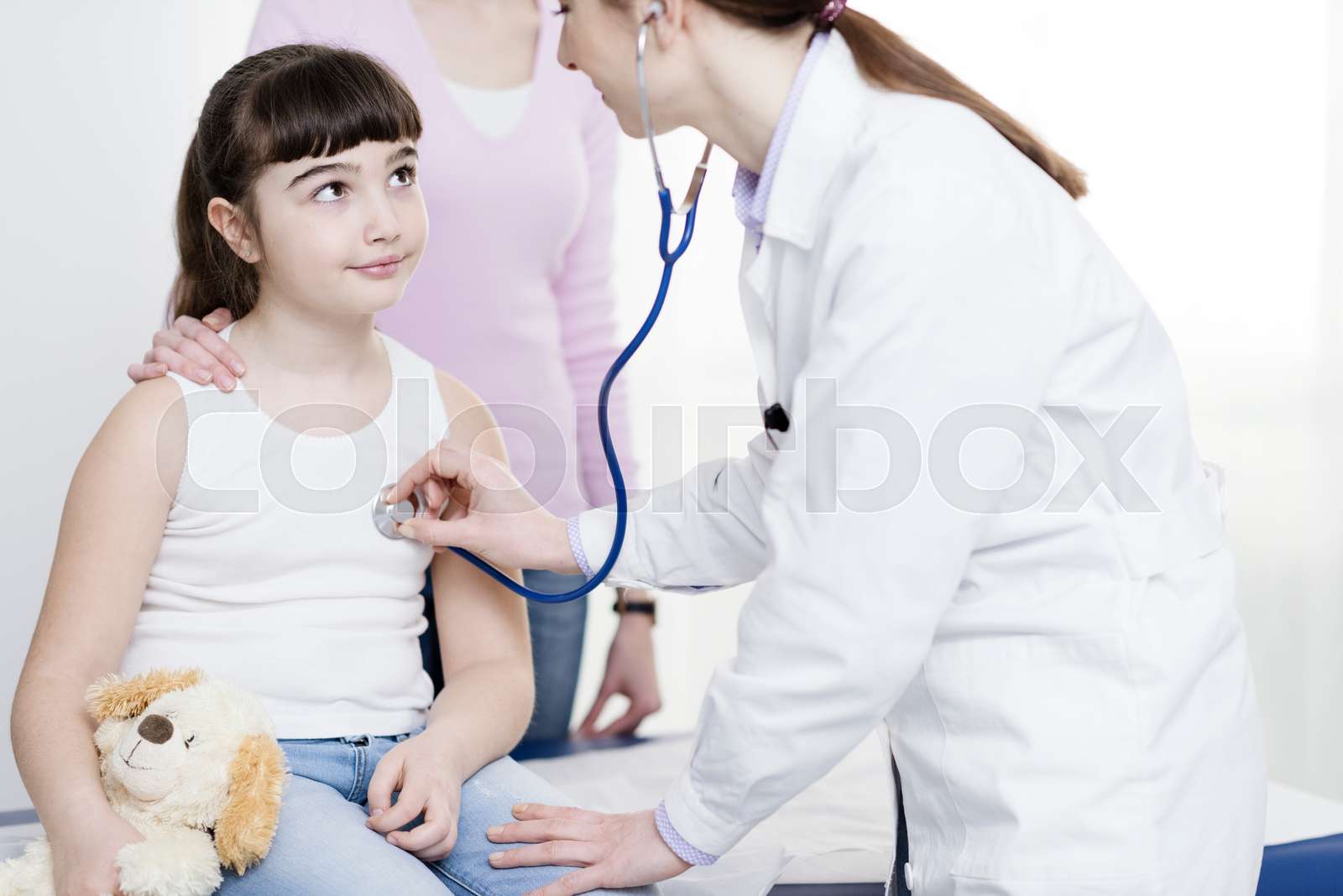 Doctor examining a cute smiling girl with a stethoscope | Stock image ...