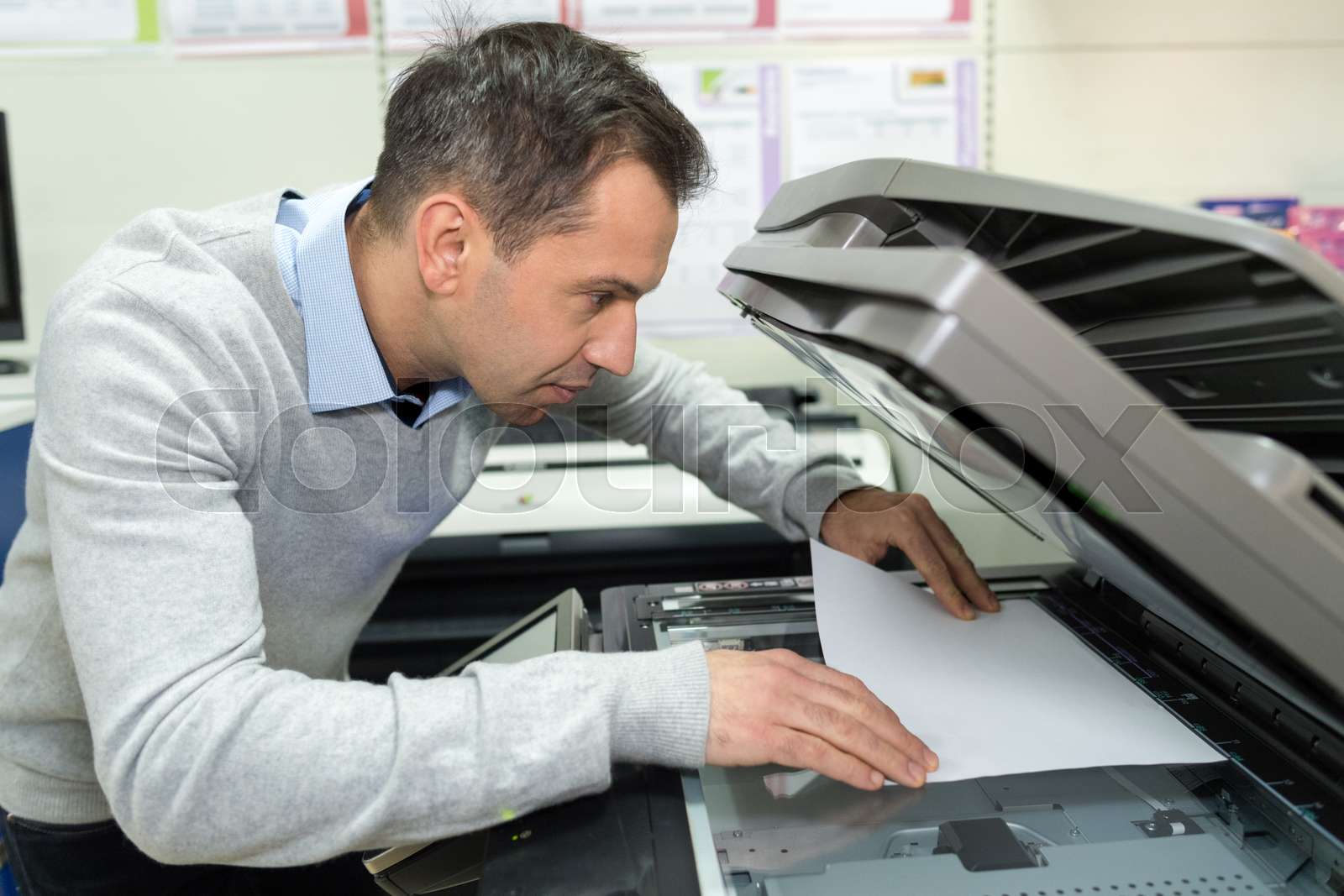 man placing paper onto photocopier | Stock image | Colourbox