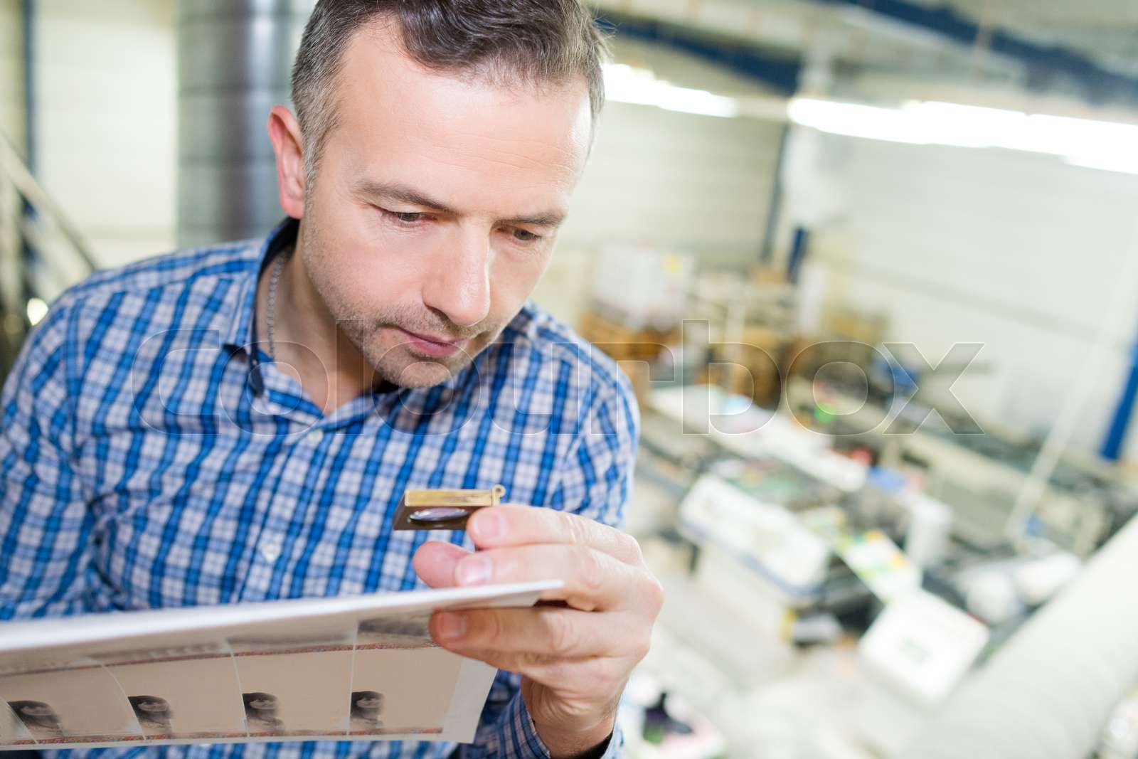 printing press worker inspecting produced page with magnifier | Stock ...