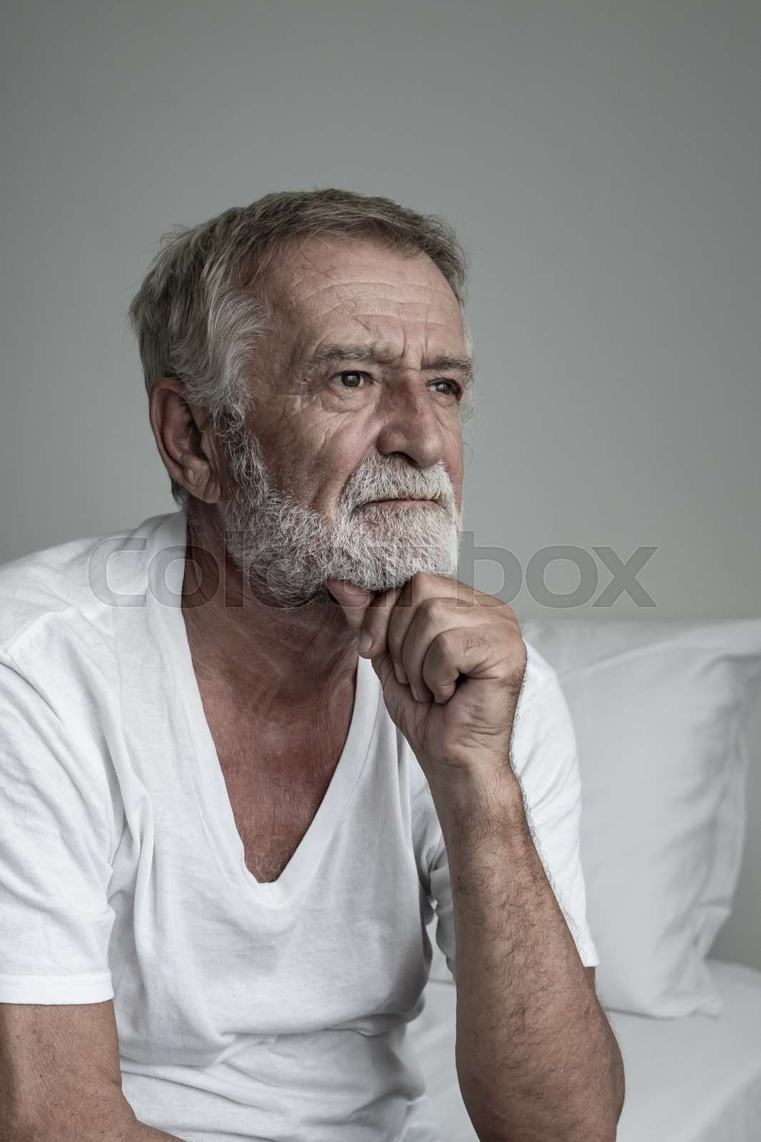senior man thinking or try to remember alone on bed in white room ...