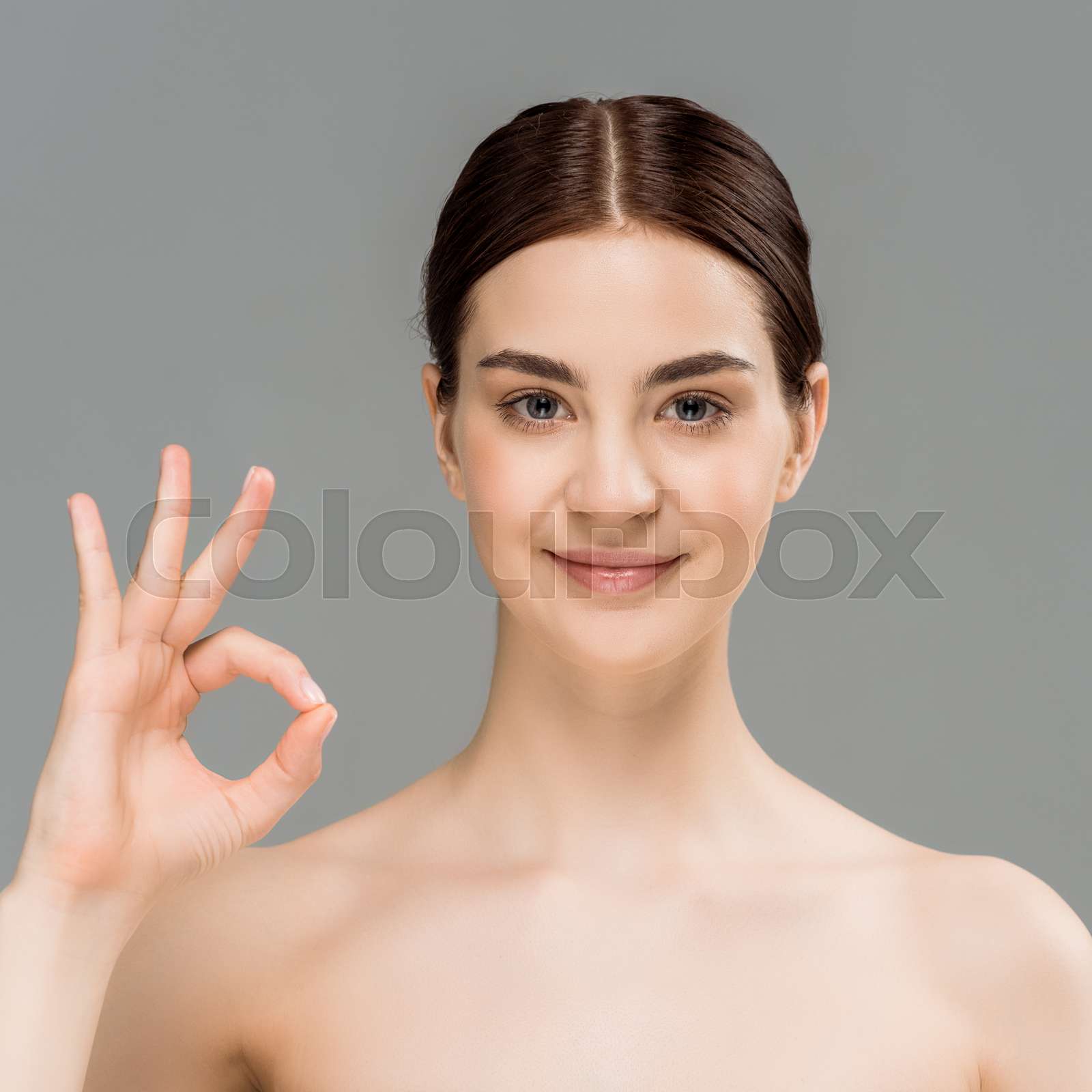 cheerful young naked woman showing ok sign isolated on grey | Stock image | Colourbox