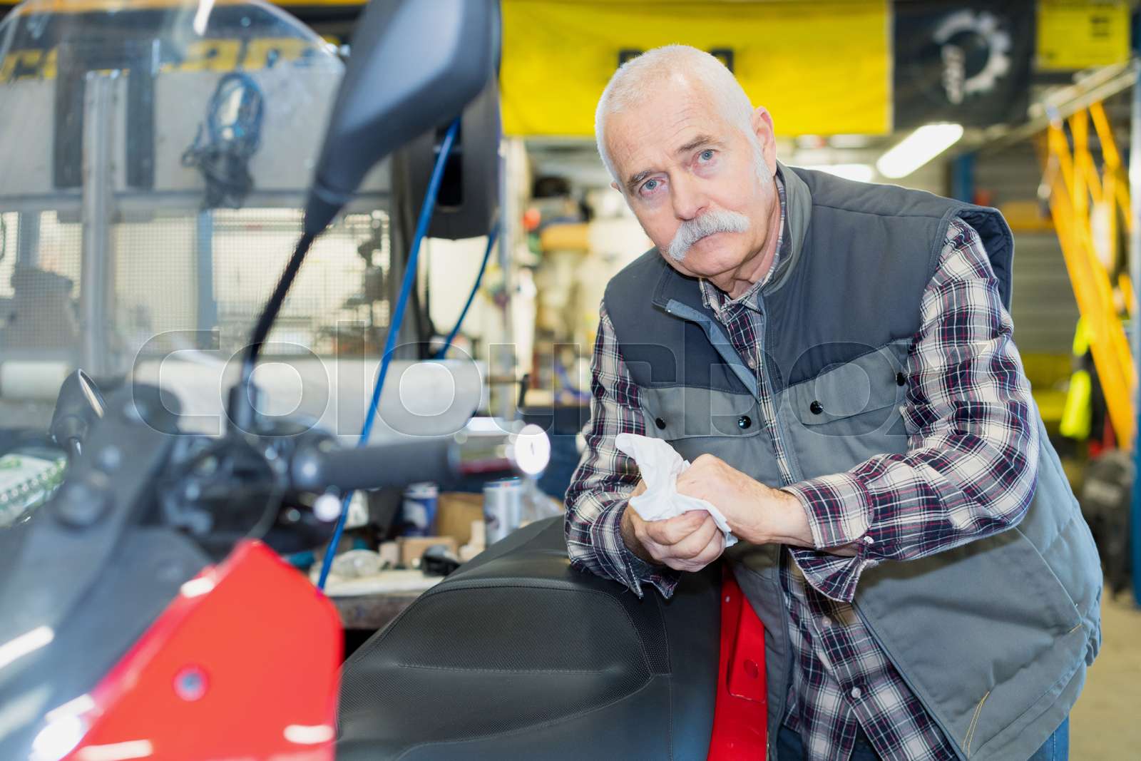 senior mechanic servicing a scooter | Stock image | Colourbox