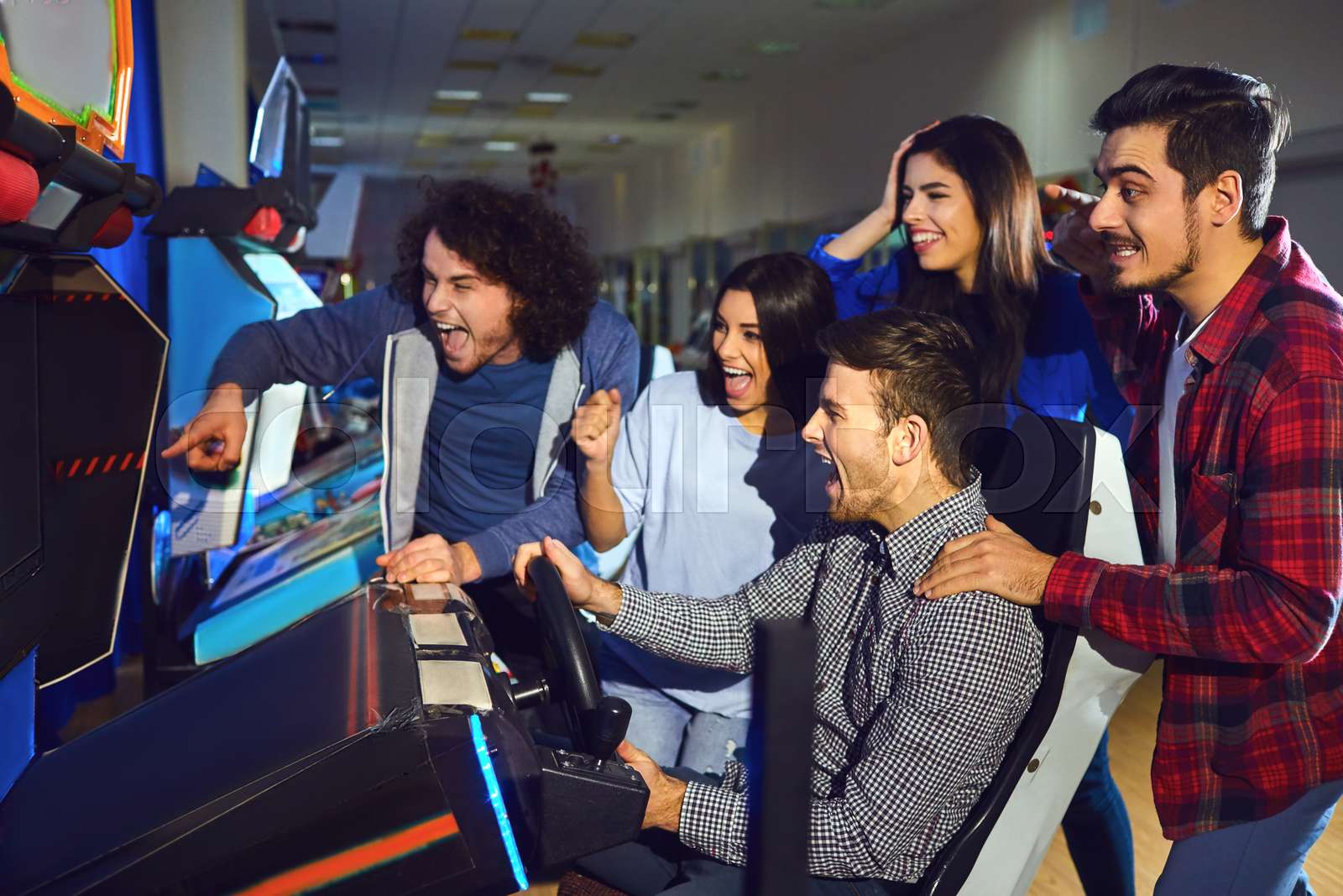 A group of friends playing arcade machine. | Stock image | Colourbox