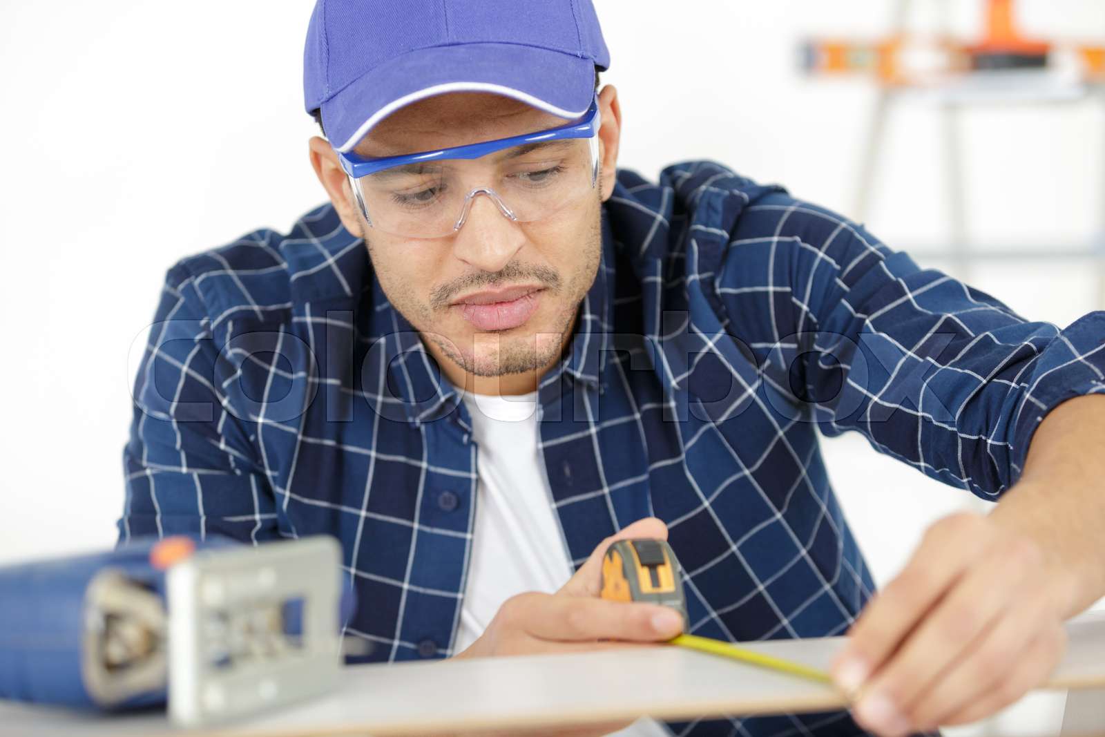 man measuring wood with tape measure | Stock image | Colourbox