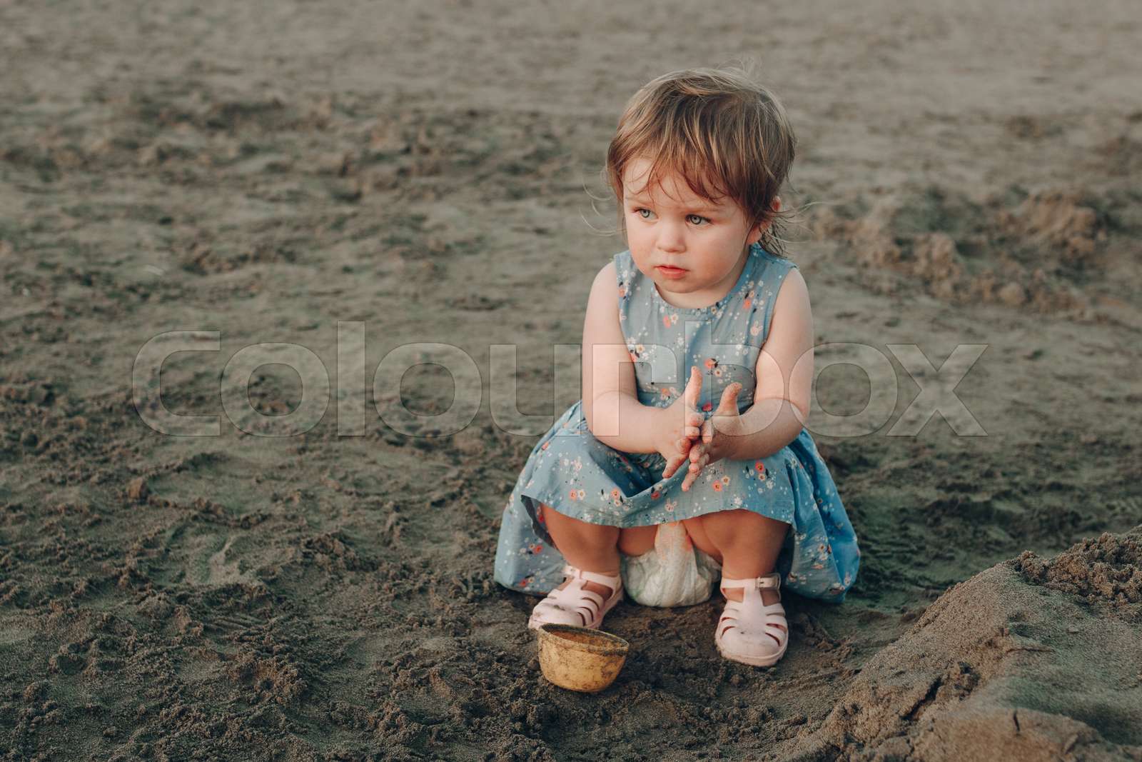 Little caucasian girl have fun digging in the sand at ocean beach ...
