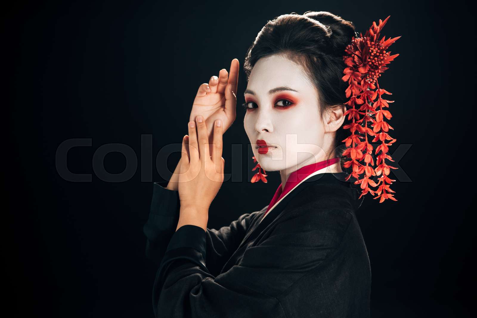 side view of beautiful geisha in black and red kimono and flowers in ...