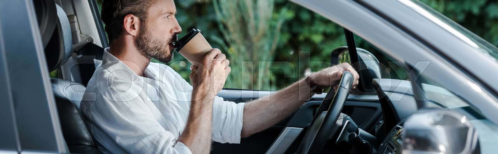 panoramic shot of man drinking coffee to go while driving car | Stock ...