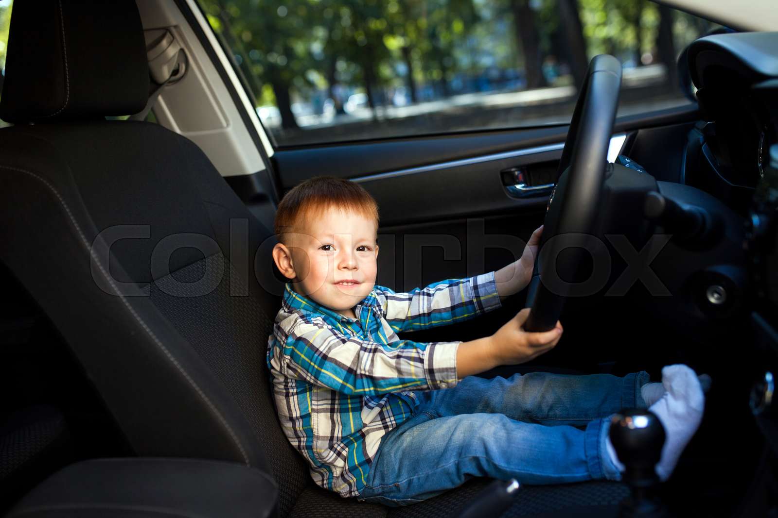 Cute little boy smiling and driving fathers car | Stock image | Colourbox