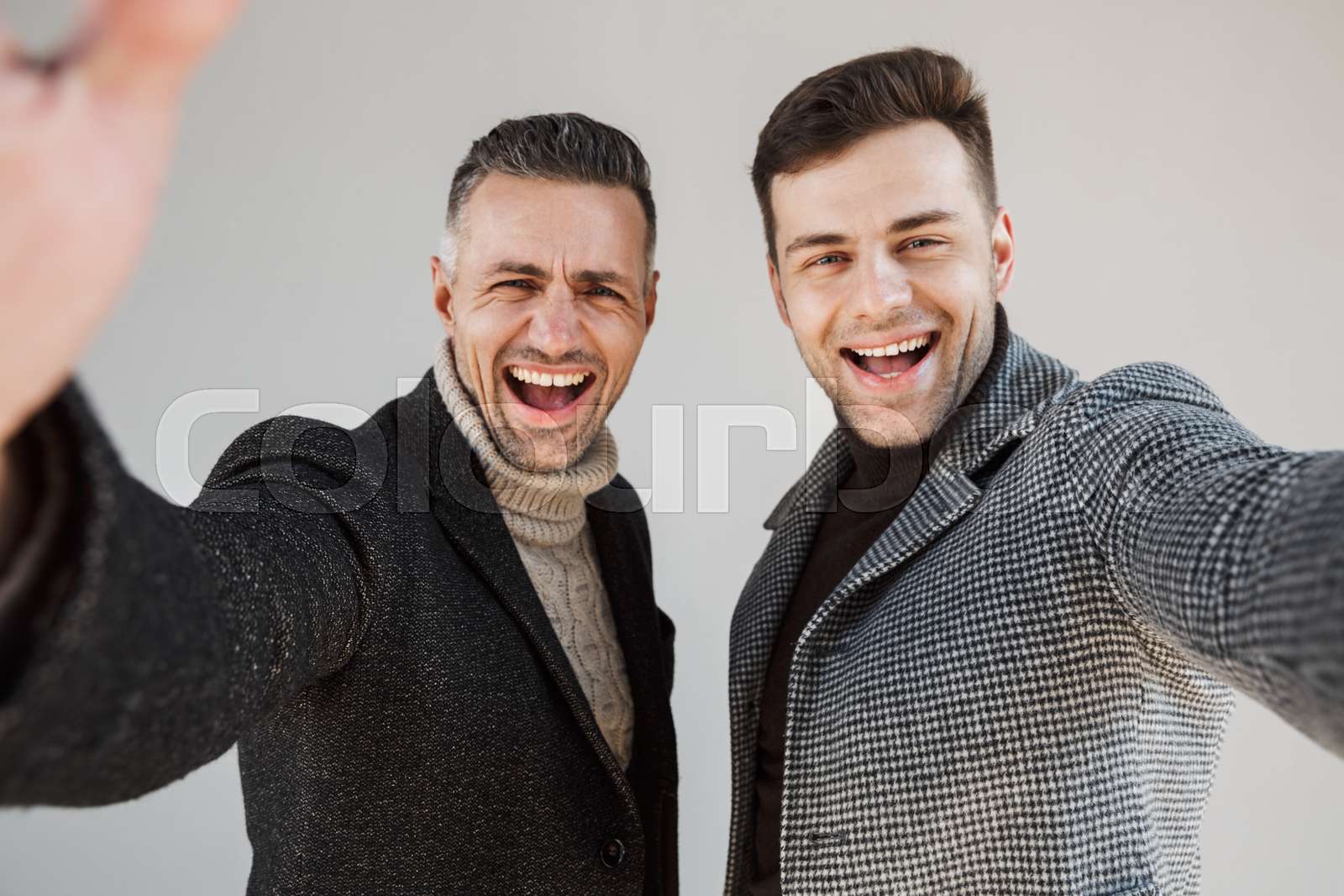 Two handsome men wearing coats over gray background | Stock image ...