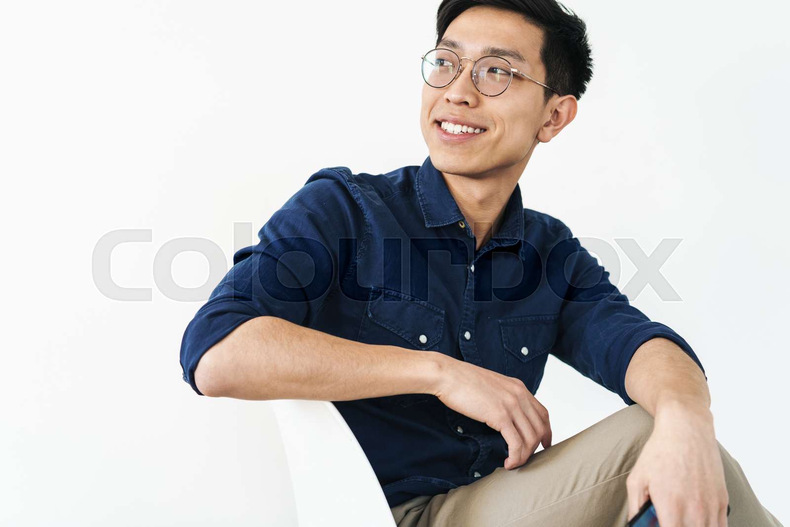 Photo closeup of handsome asian man sitting in chair and looking aside ...