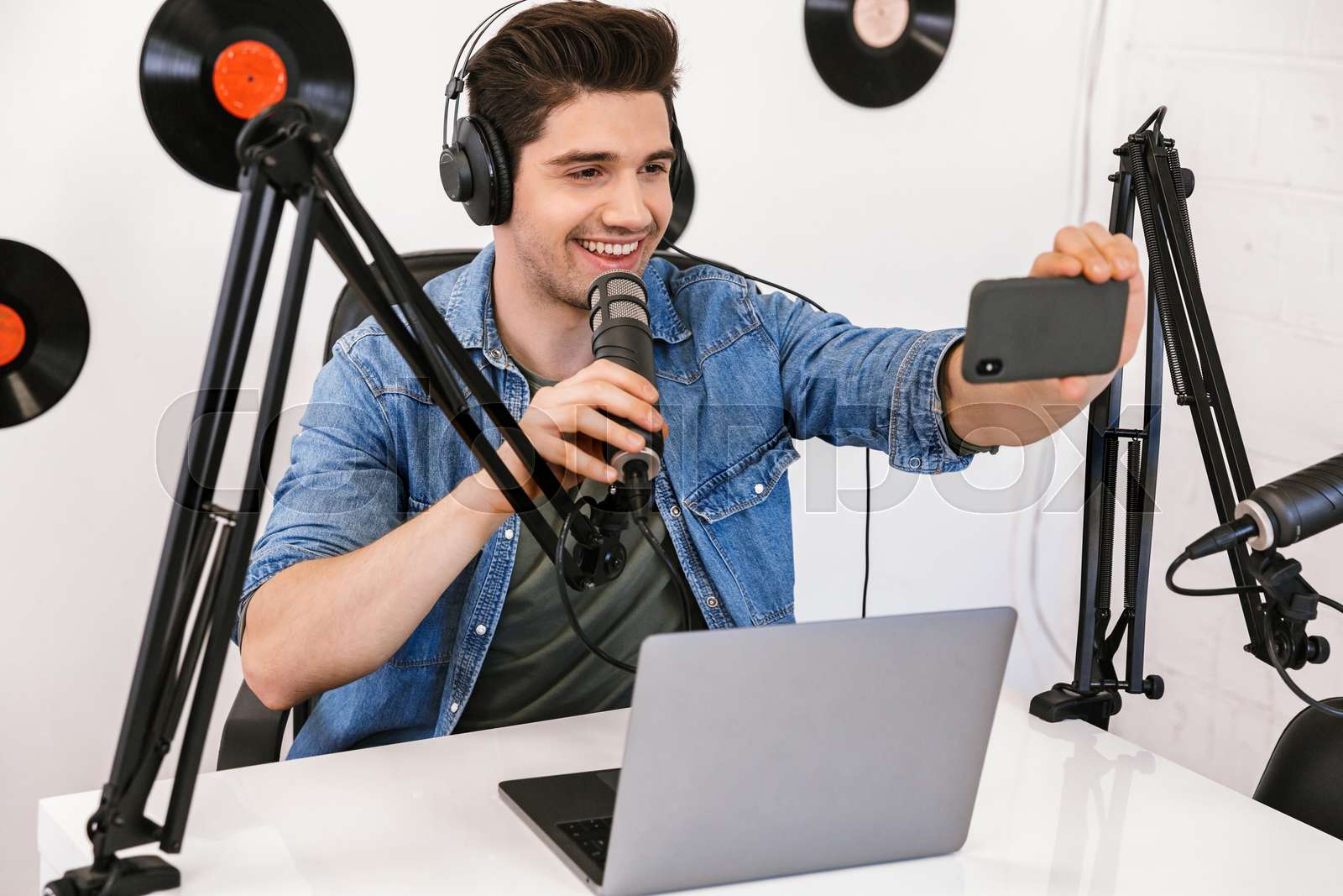 Handsome young man radio host at the workspace with microphone and ...