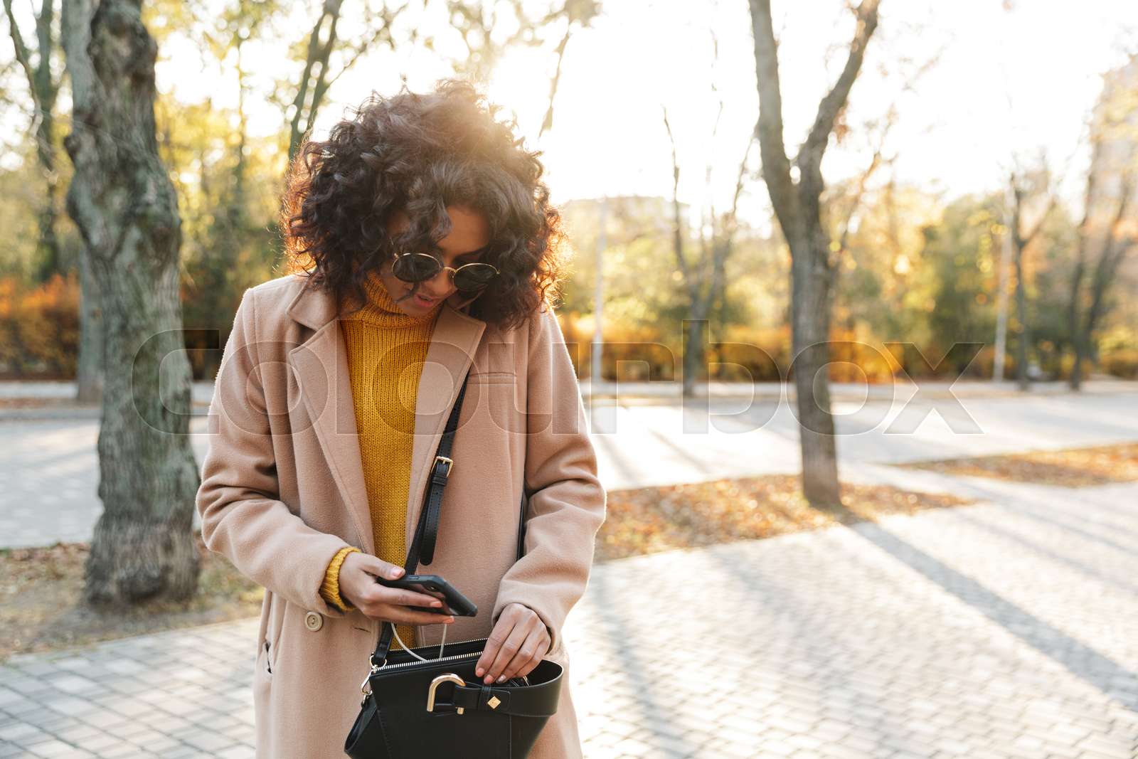 Beautiful young african woman walking outdoors in a spring park using ...